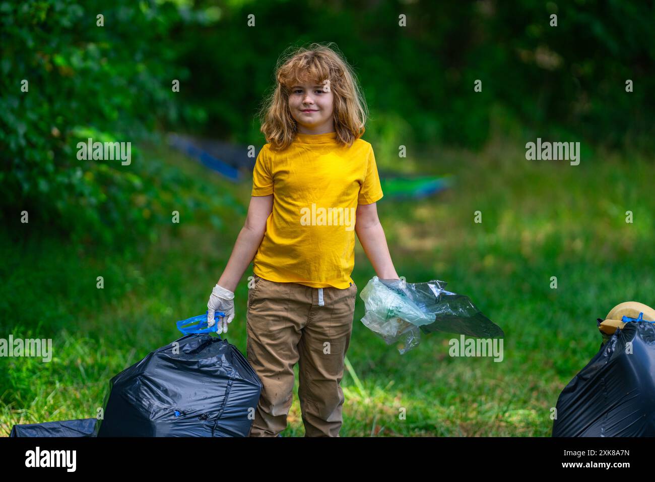 Kid with bin bag full of waste and trash tongs during garbage ...