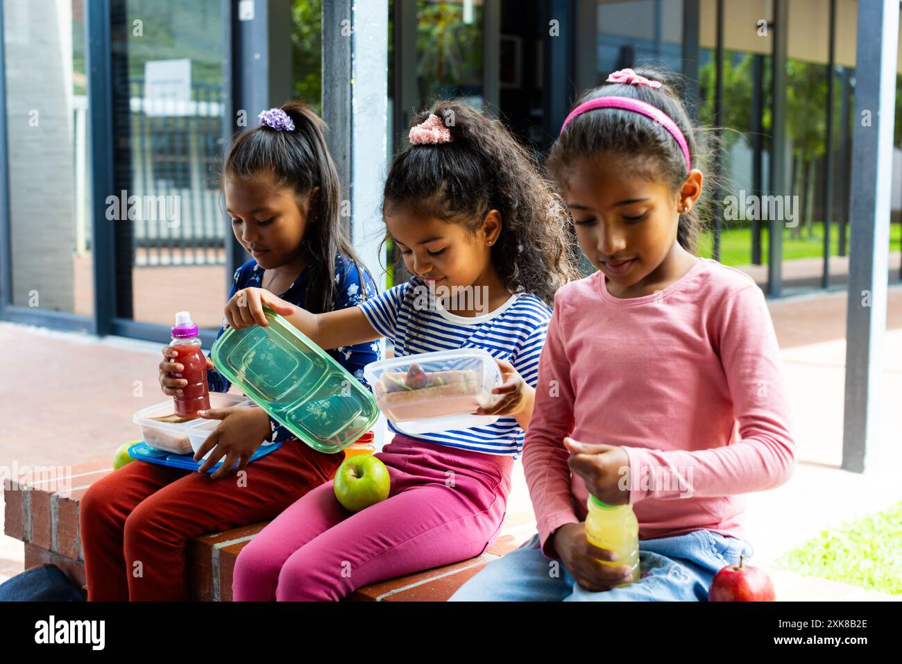 Three students share lunch, showing joy and diversity Stock Photo - Alamy