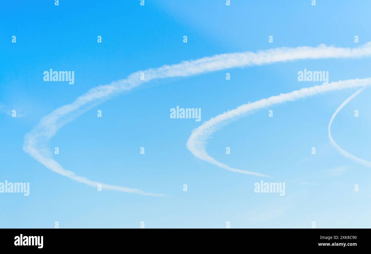 White vapor trails create curved patterns against a clear blue sky ...