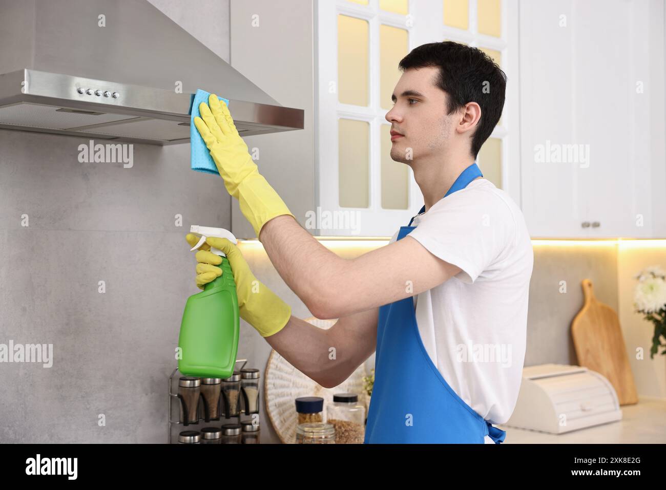 Professional janitor wearing uniform cleaning kitchen hood with rag and ...
