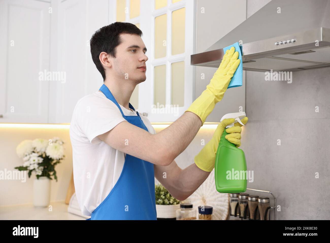 Professional janitor wearing uniform cleaning kitchen hood with rag and ...