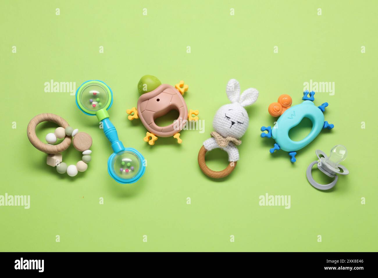 Different baby rattles on green background, flat lay Stock Photo - Alamy