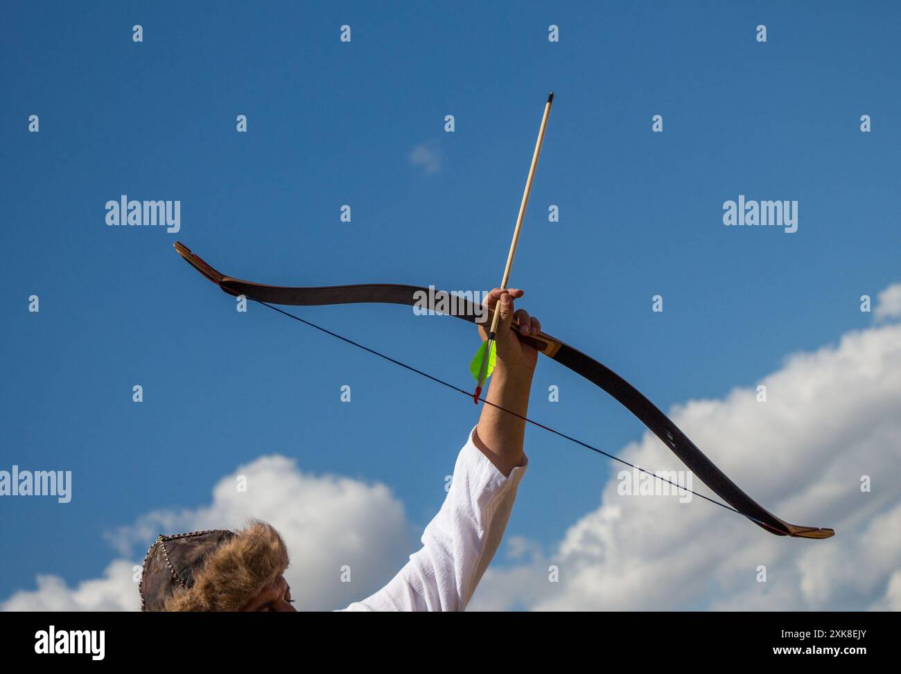 Archer with bow in traditional clothes shooting an arrow Stock Photo ...