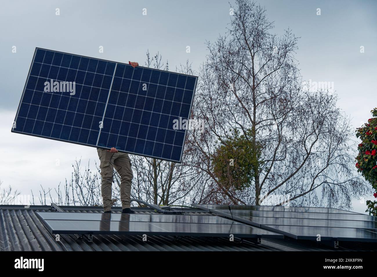 A person installing grid-tied solar panels on a traditional Kiwi villa ...