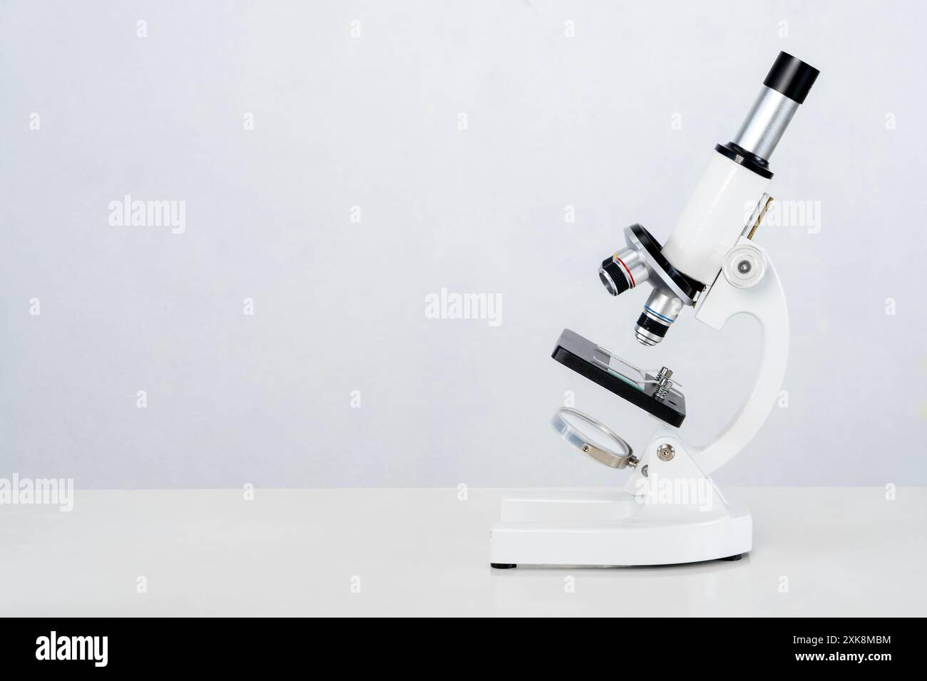 White microscope on table, microscope against white background. Light ...