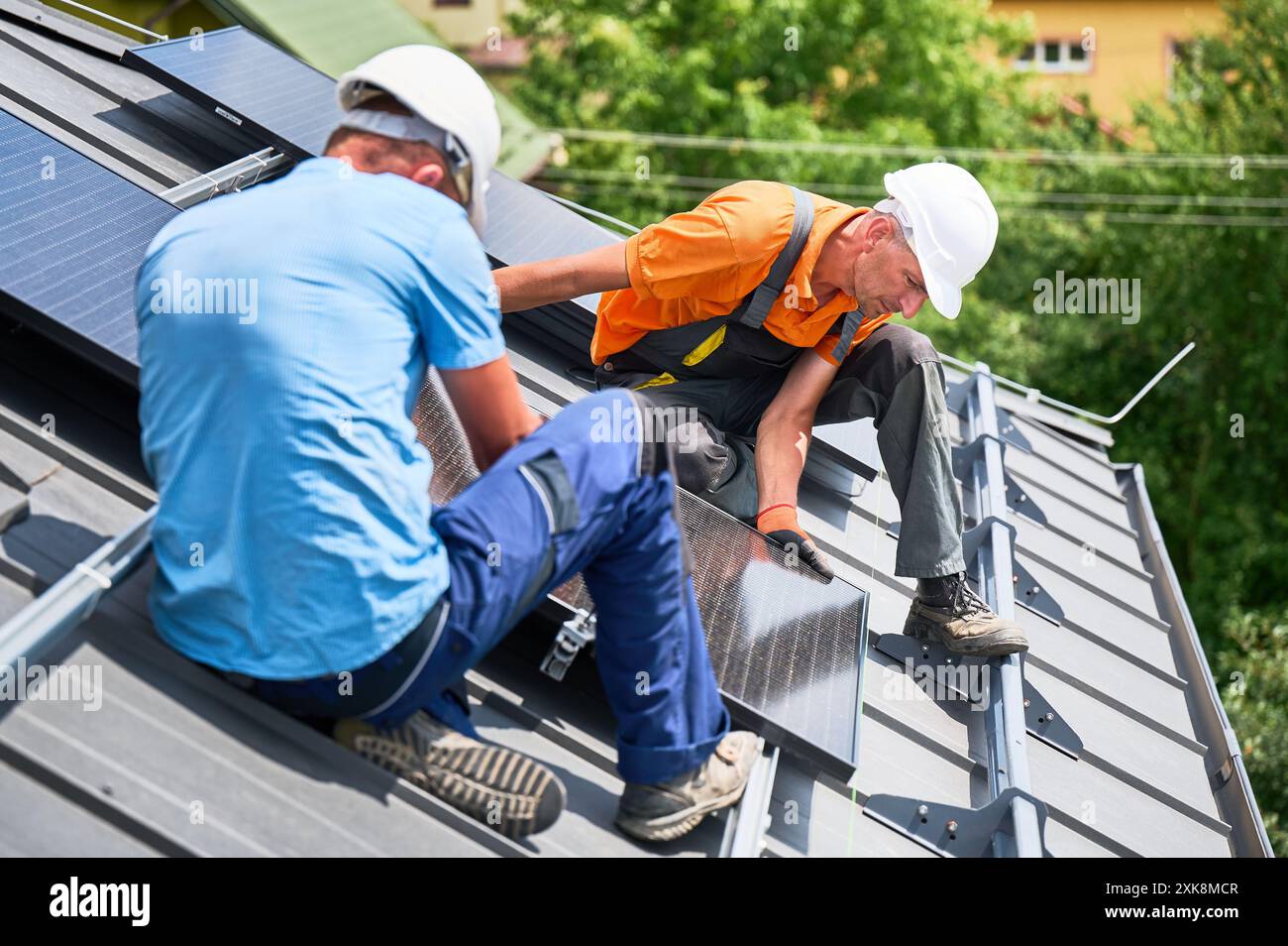Workers building solar panel system on rooftop of house. Two men ...