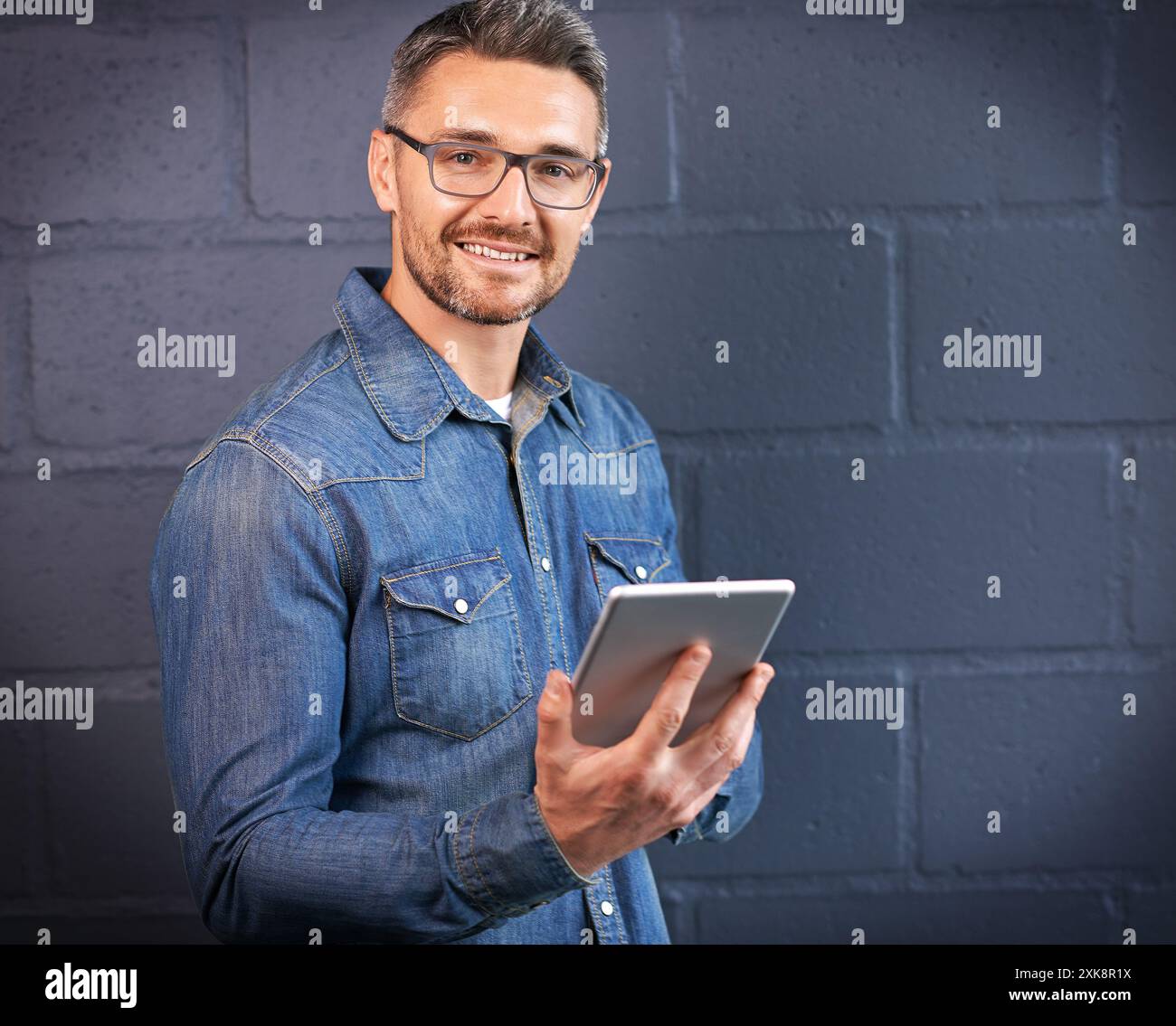 Portrait smile, man and tablet by brick wall for online communication ...