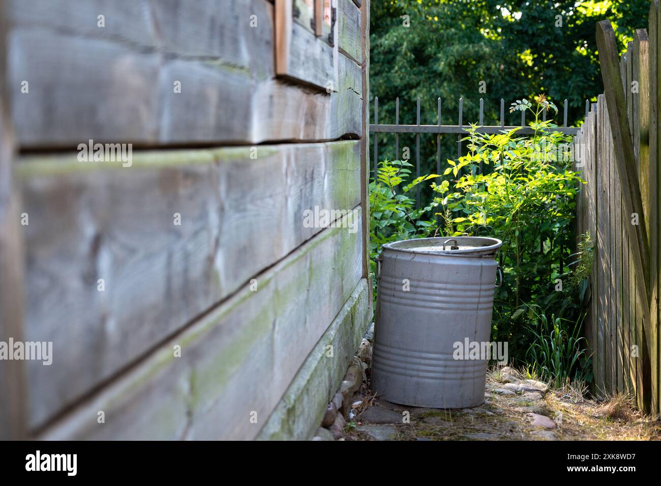 tin waste bin outside an old wooden cottage in a village Stock Photo ...