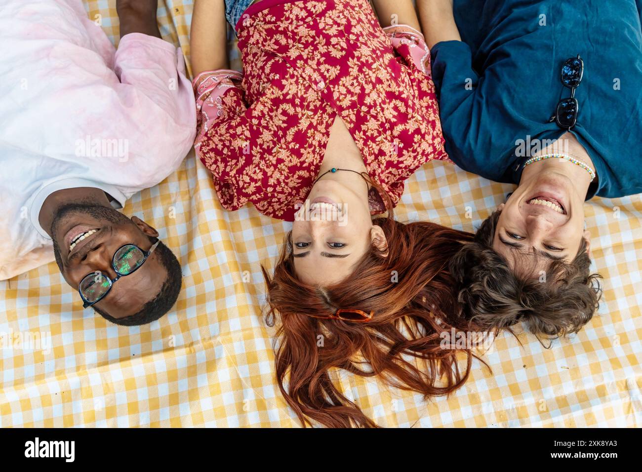 Overhead view of diverse group of young friends lying on yellow ...