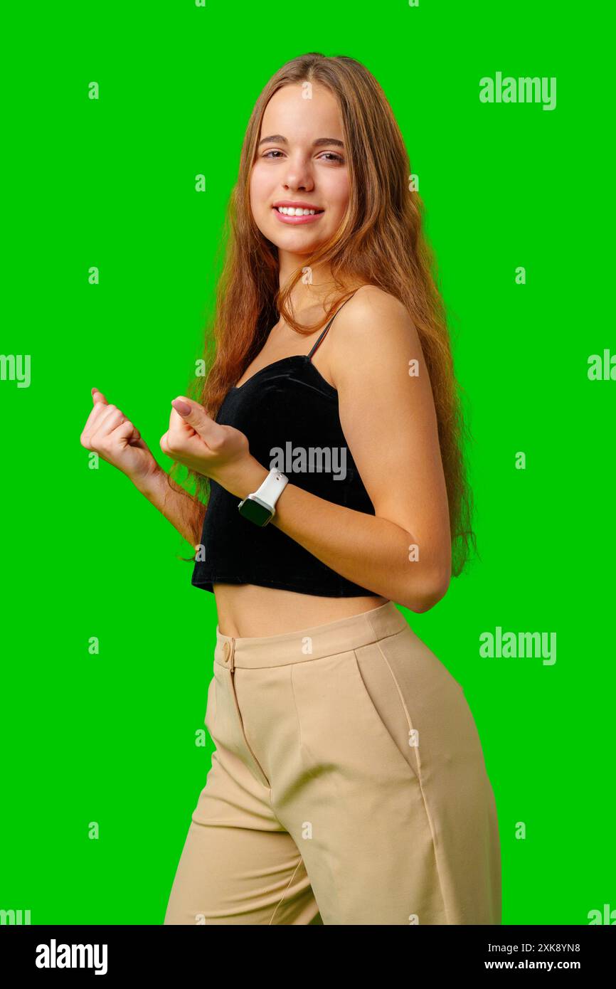 Young Woman Celebrating Success With Raised Fists Against Green Screen ...