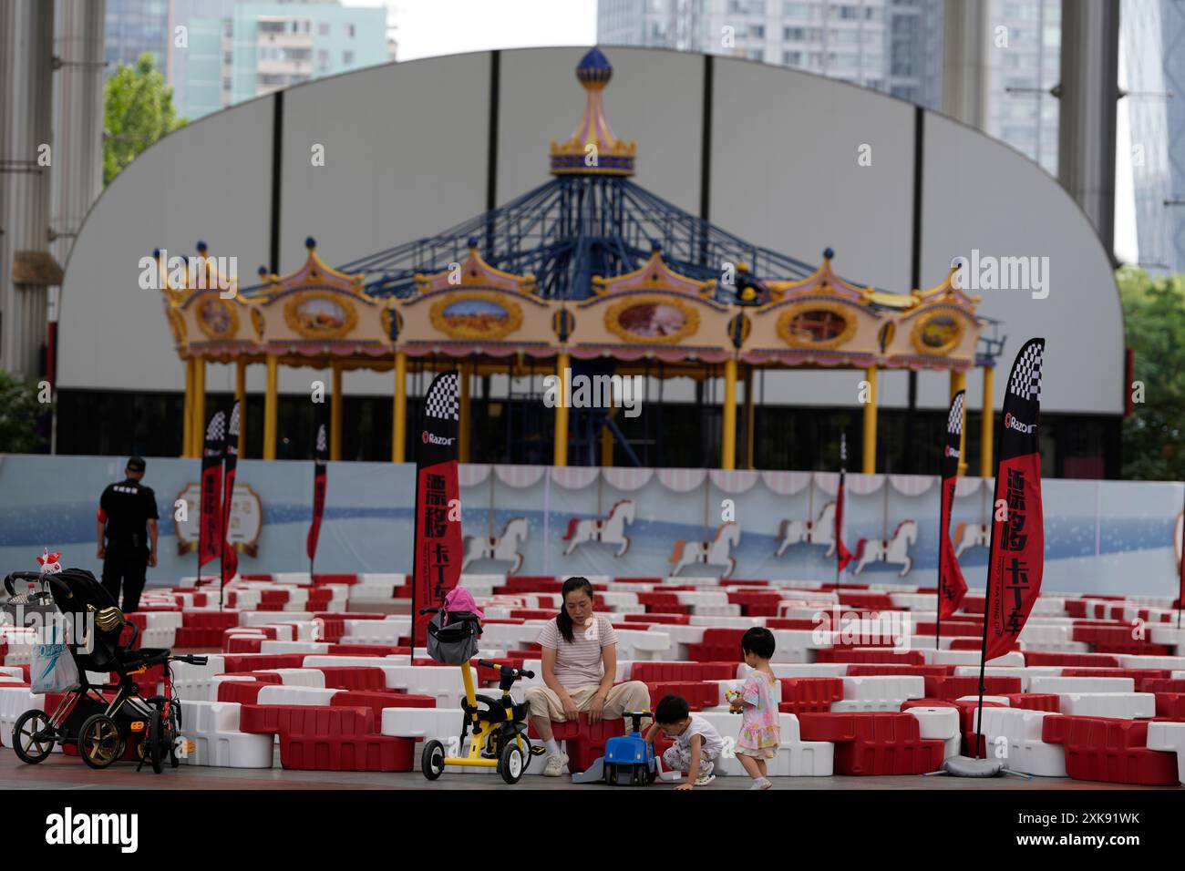 A woman attends to children near a mall with a go-kart track and merry ...