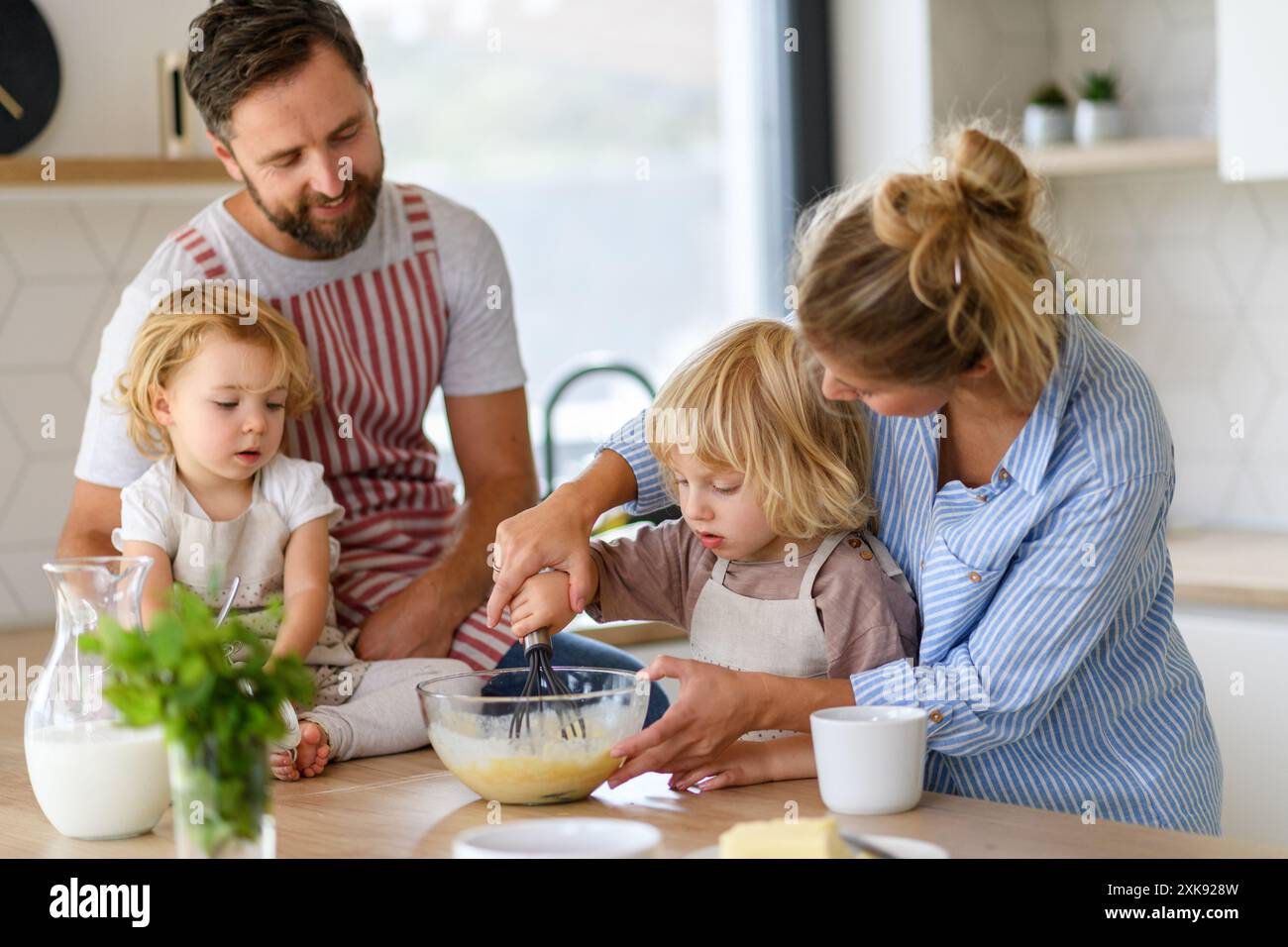 Young nuclear family making pancakes together. Parents and children in ...