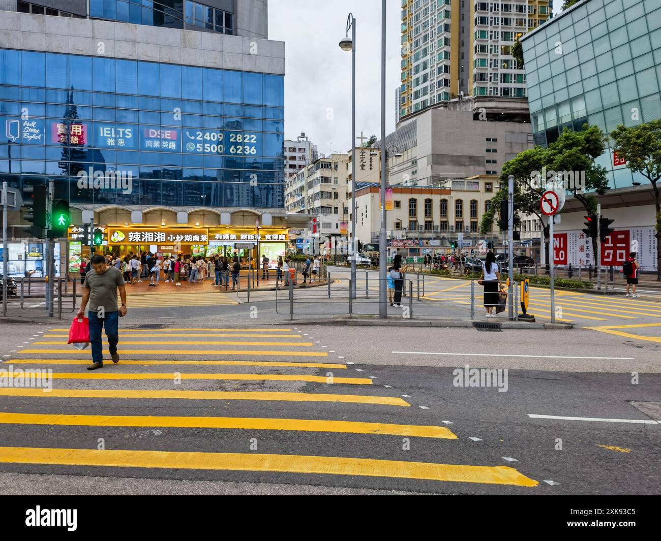 Hong Kong, China - July 21, 2024 : A man walks across a crosswalk with ...