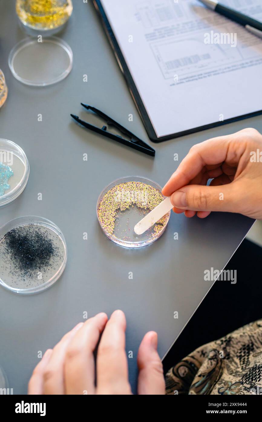 Female scientist hands taking sample of small plastic particles from ...