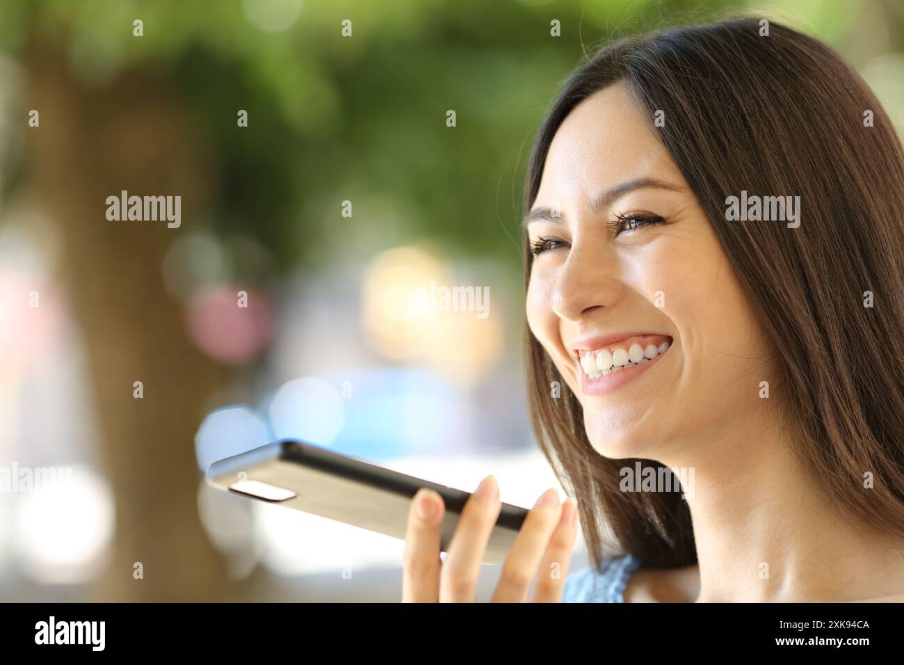 Happy asian woman dictating message on phone standing outdoors Stock ...