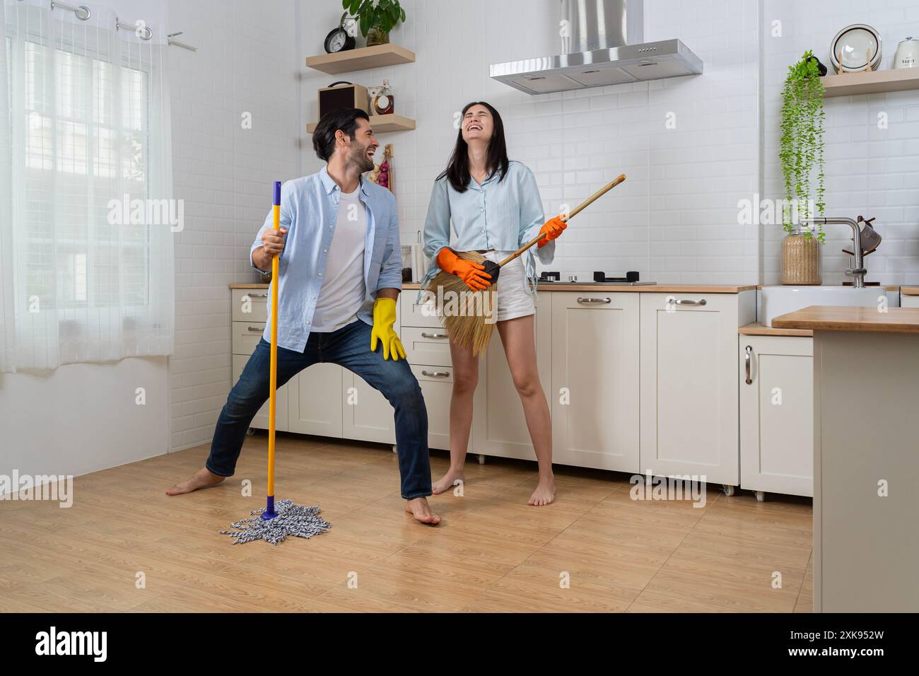 Joyful woman singing songs and dancing with closed eyes while cleaning ...
