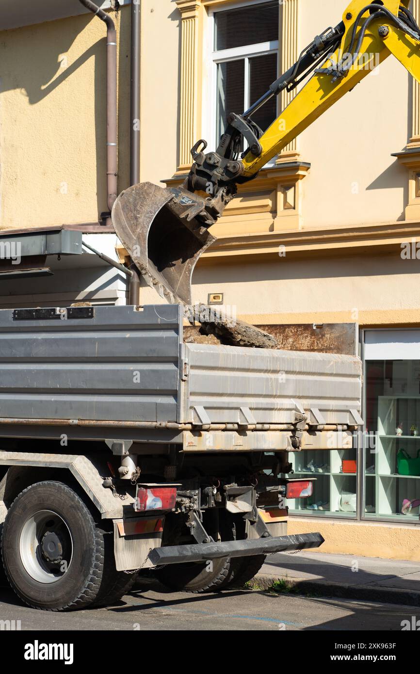 Excavator bucket piles old asphalt into truck bed Stock Photo - Alamy