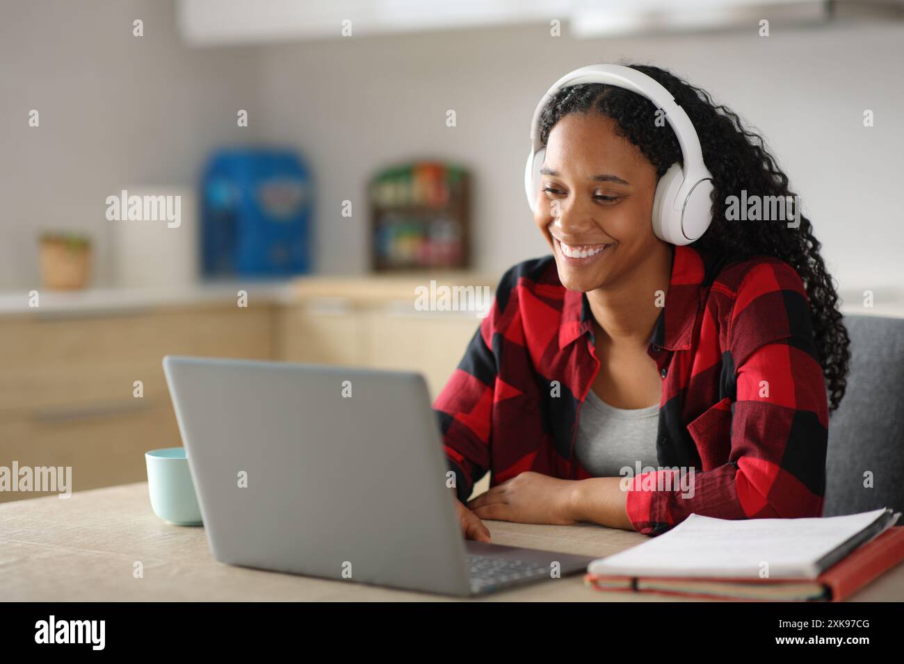 Black student e-learning with laptop and headphone in the kitchen at ...