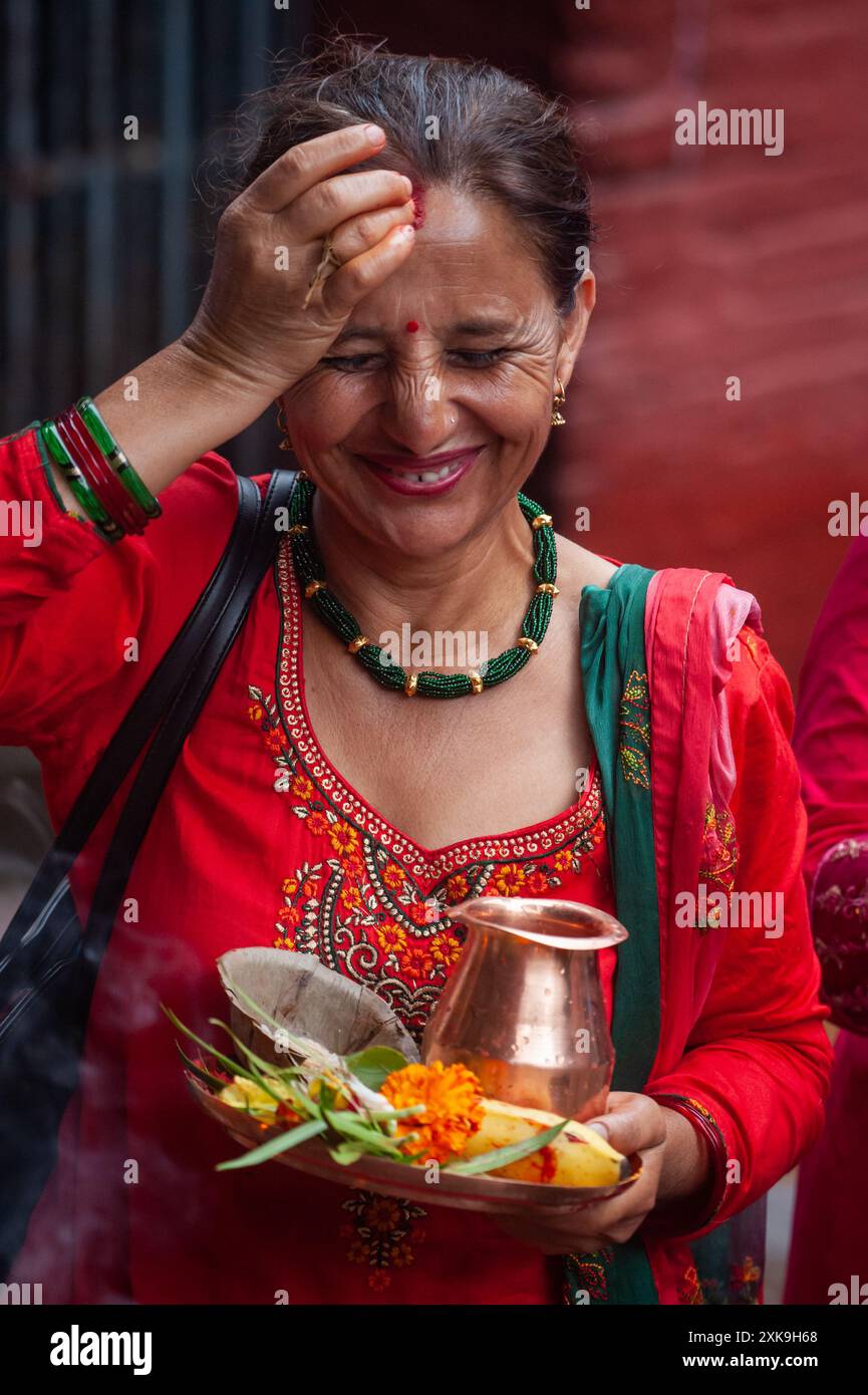 Lalitpur, Nepal. 22nd July, 2024. A woman puts tika on the forehead ...