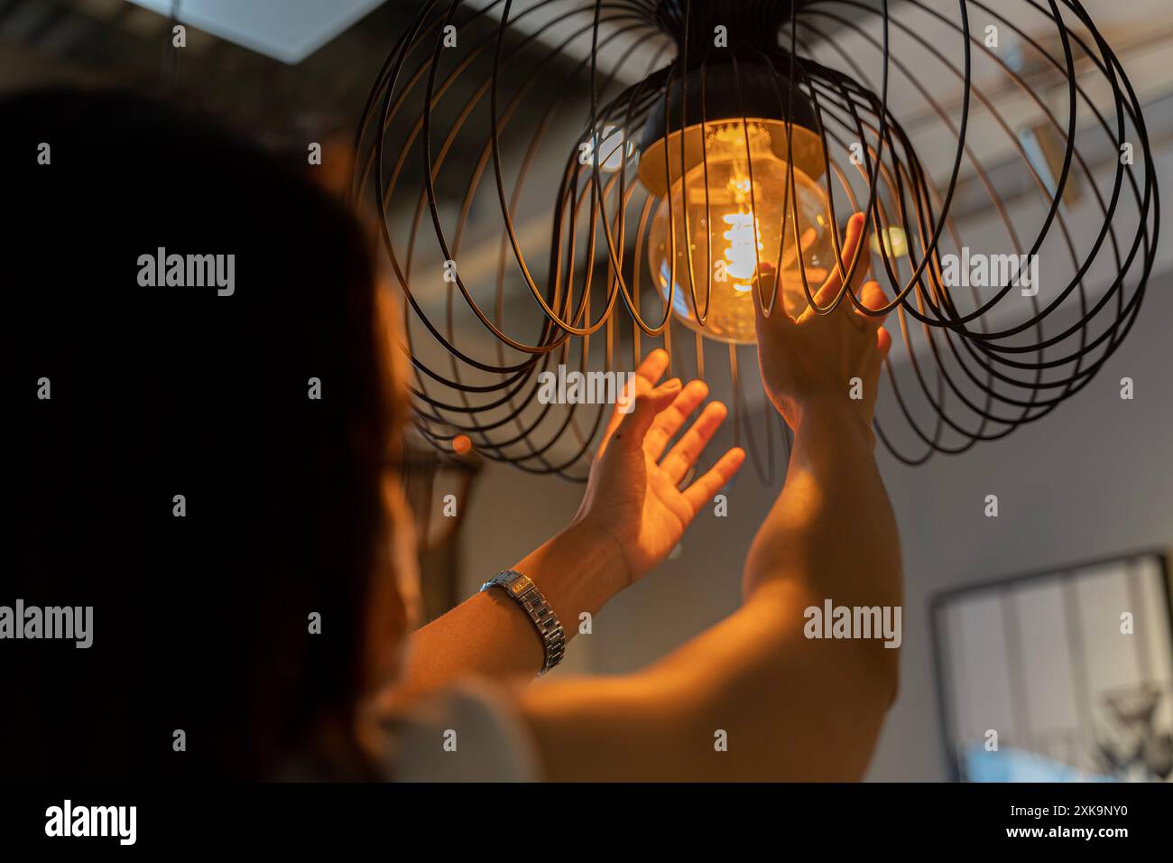 Woman changing light bulb in hanging lamp at home. Modern interior ...