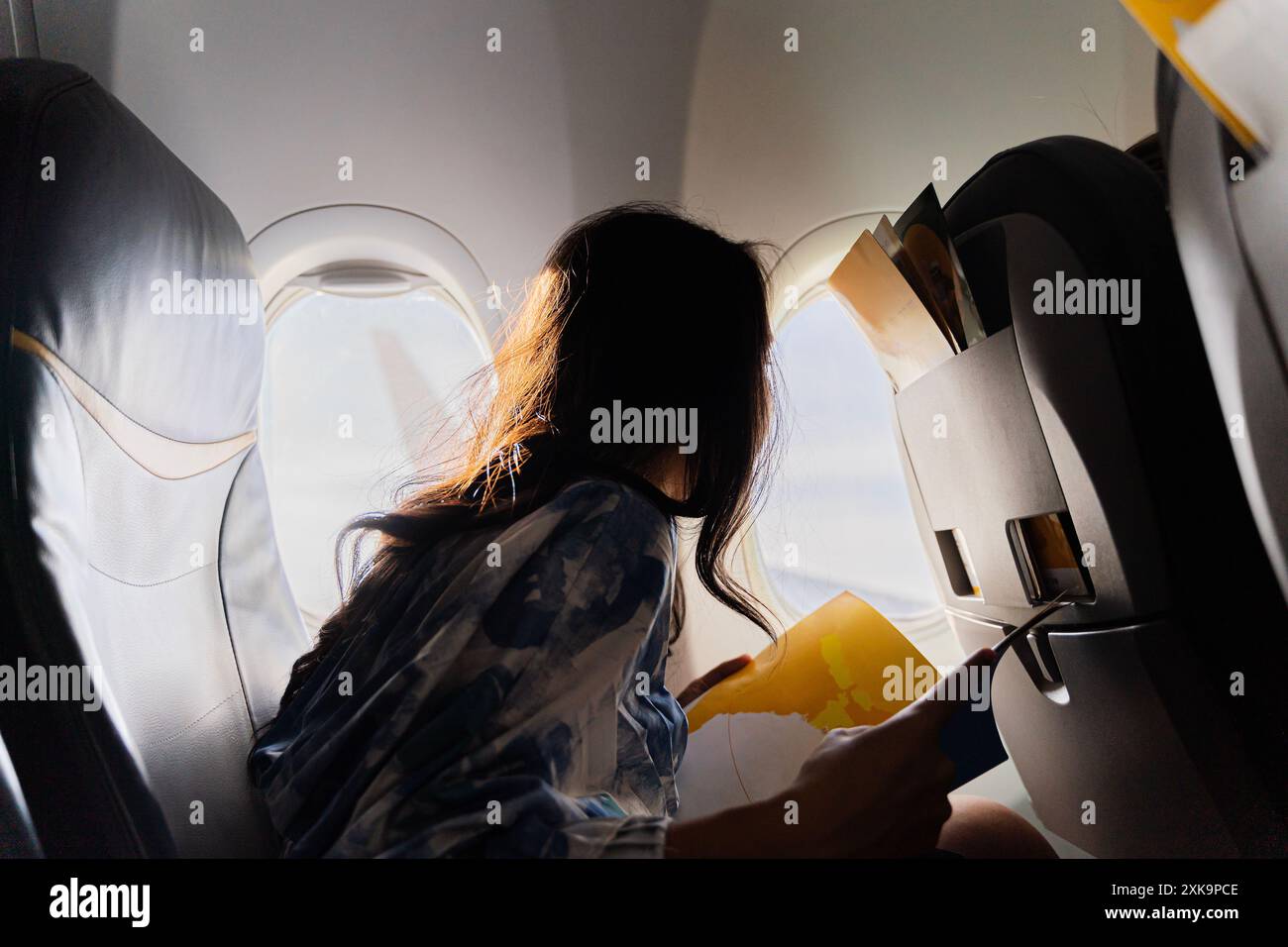 Beautiful Asian woman is reading magazine in airplane. Young woman with ...