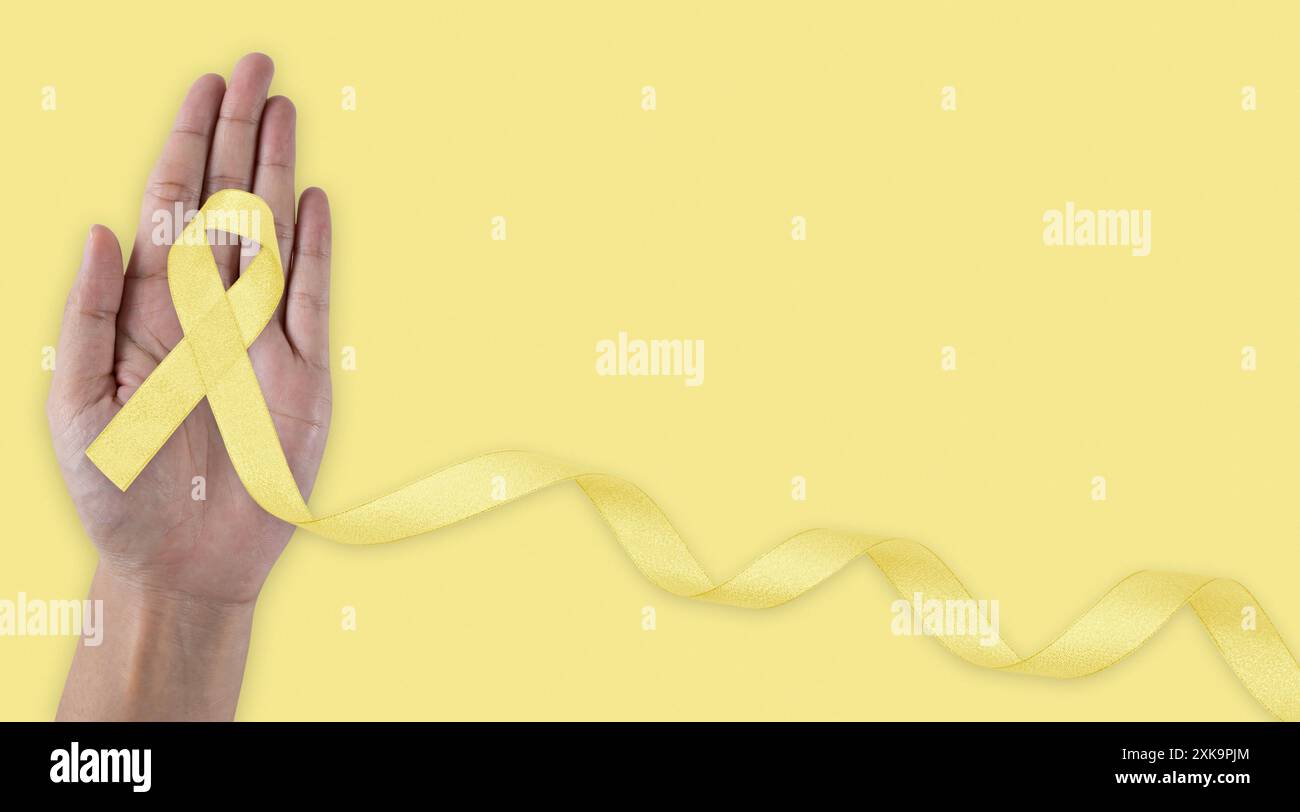 Hand holding yellow ribbon symbol of cancer awareness, medical support ...