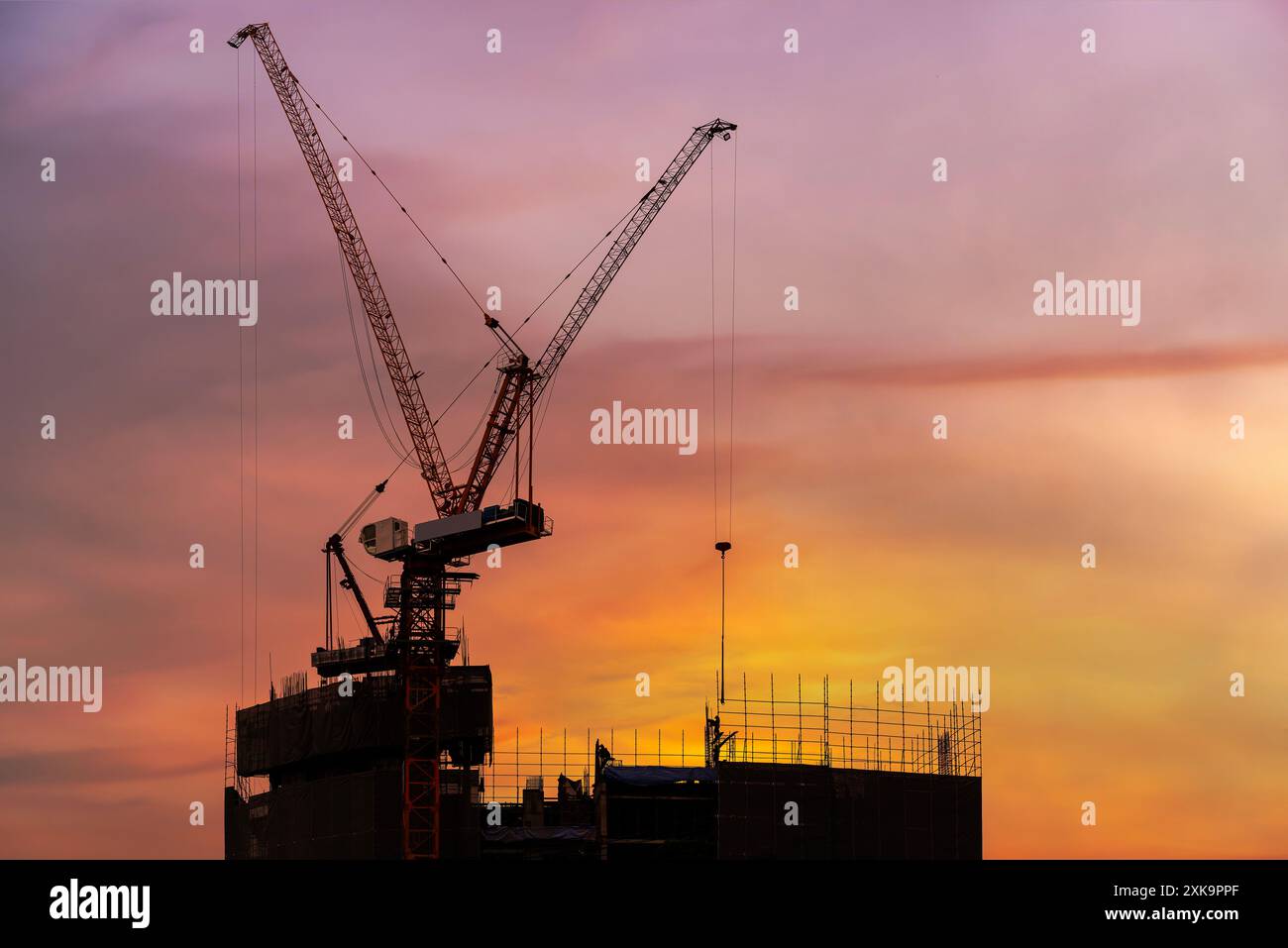 New construction site with crane and mechanical equipment on sunset ...