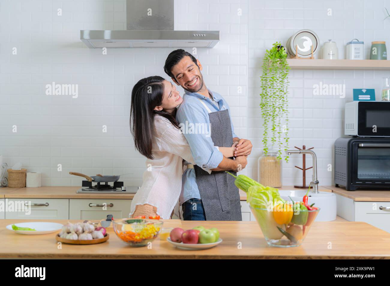 Smiling young couple cooking in kitchen.Playful cheerful biracial young ...
