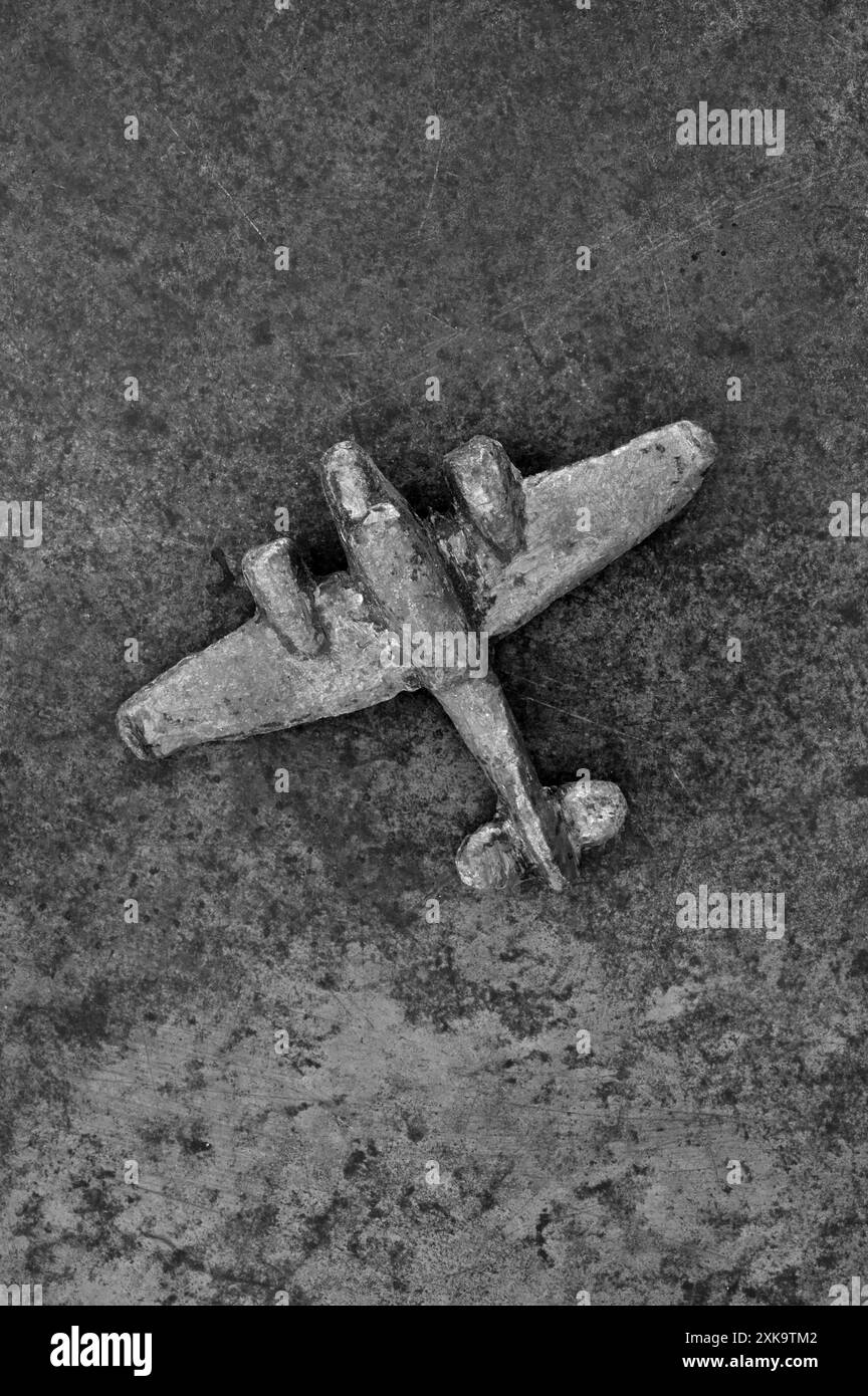 Monochrome image of vintage lead model airplane on tarnished metal ...