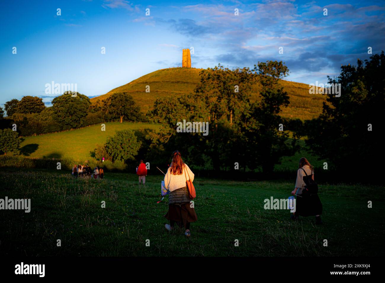 People make their way through a field at sunset on the pilgrimage of ...