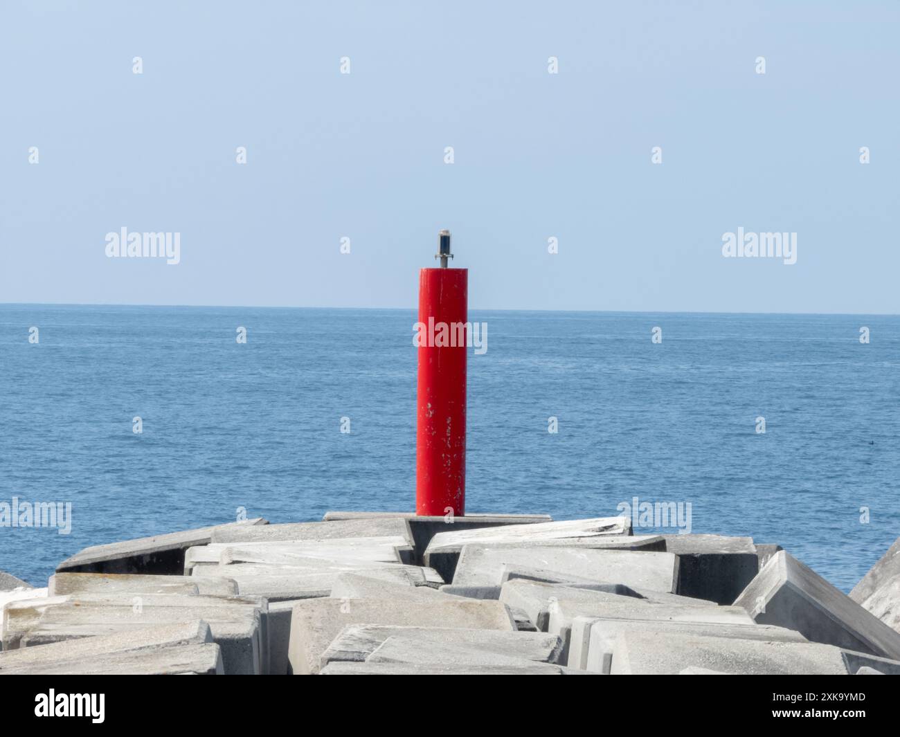Red lighthouse on the pier of concrete blocks at the port entrance ...