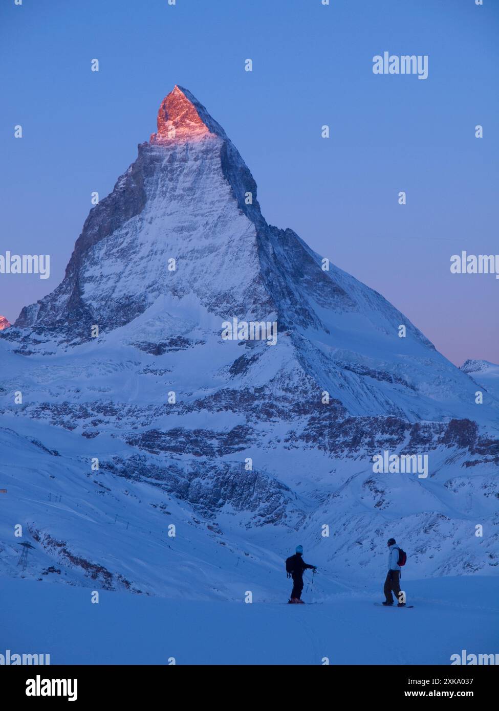 A skier and a snowboarder are staring at the Matterhorn mountain which ...