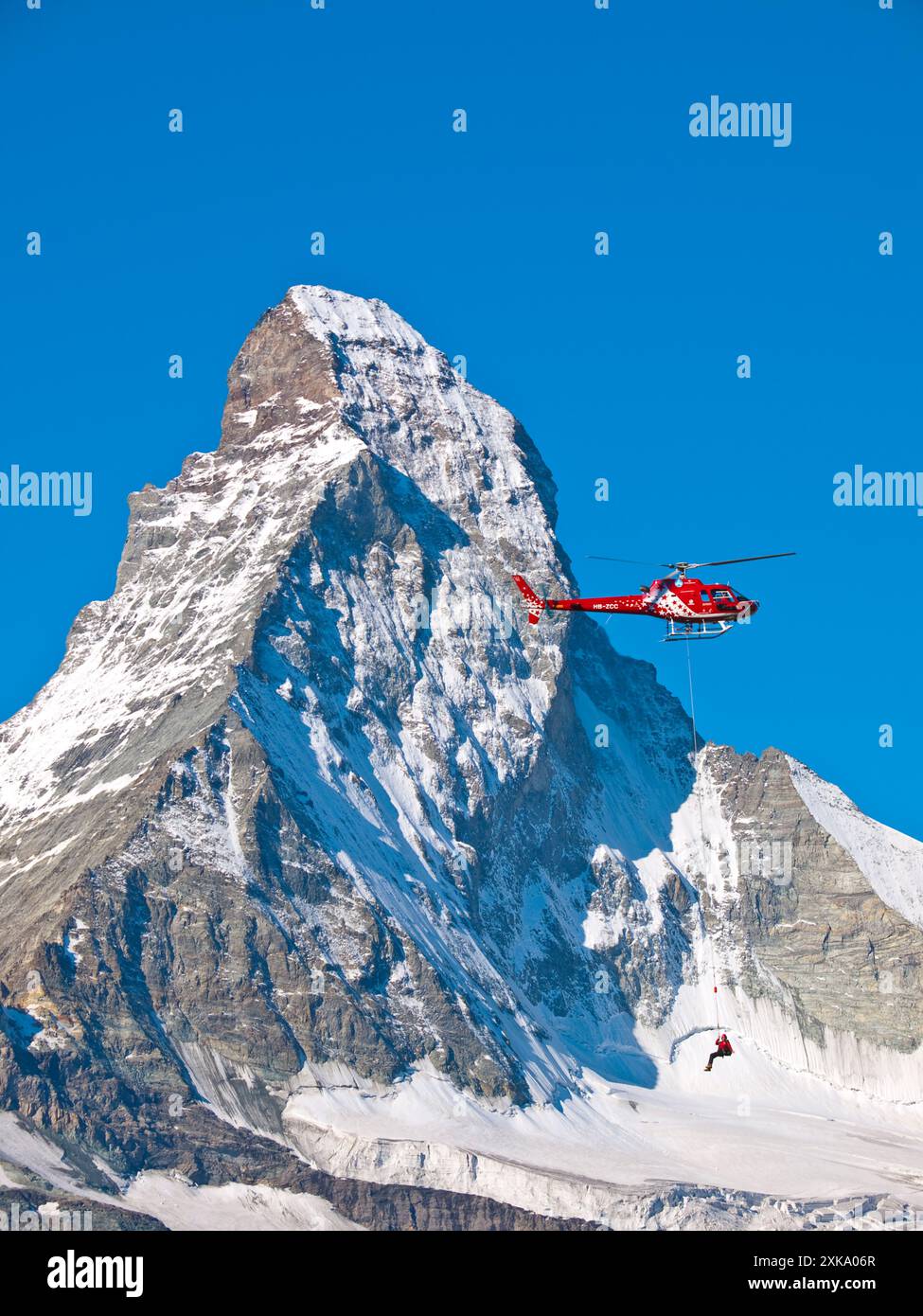 A rescue working is dangling below a helicopter of Air Zermatt in the ...