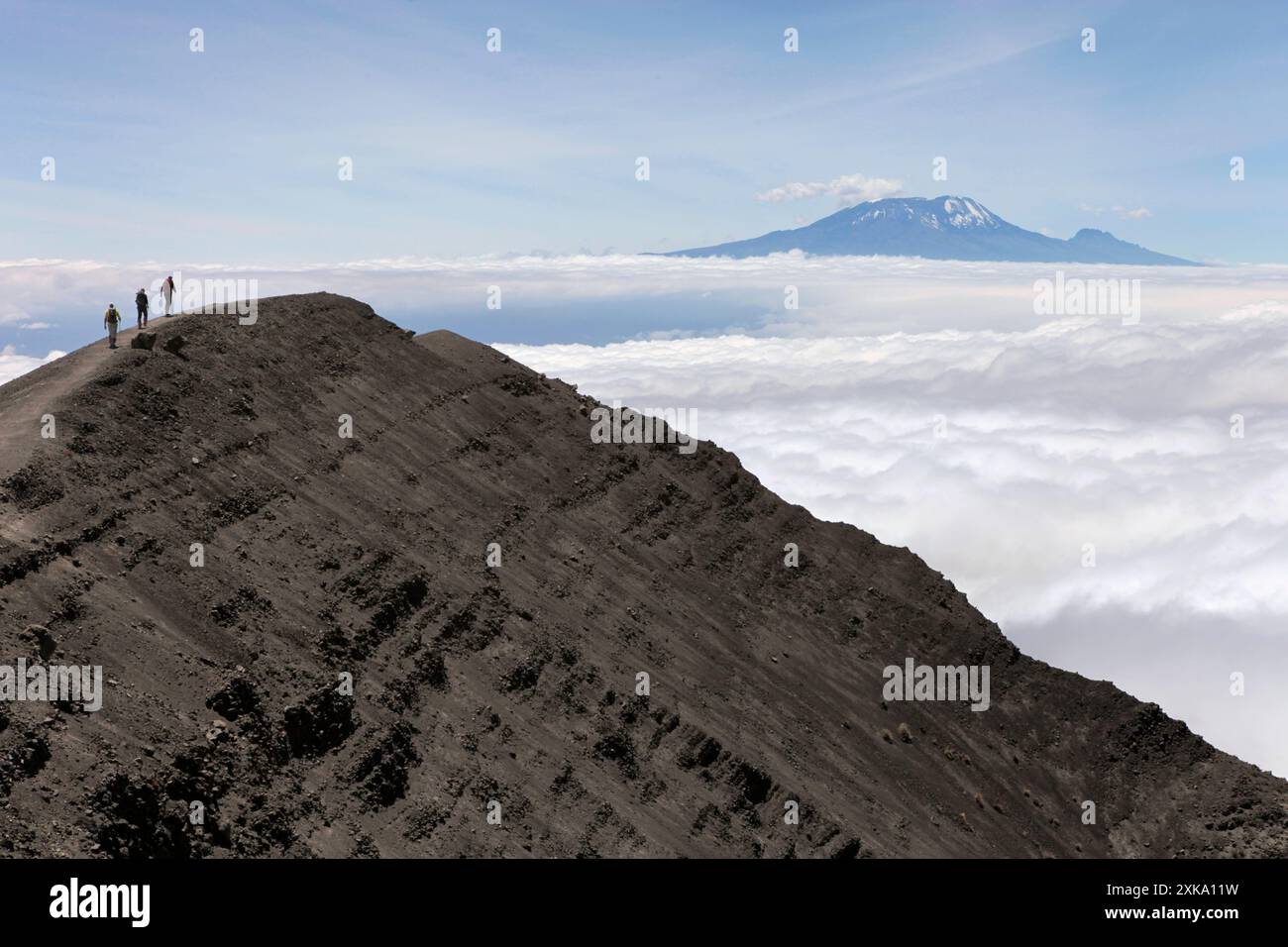 Three hikers are walking on a rocky ridge of Mount Meru, with Mount ...