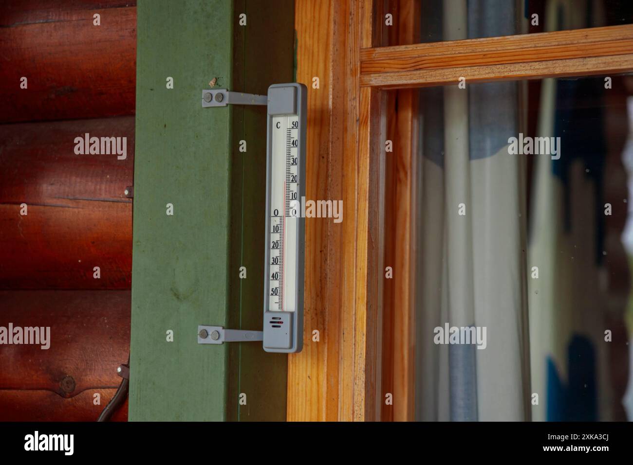 Outdoor thermometer outside the window of the wooden house is close-up ...