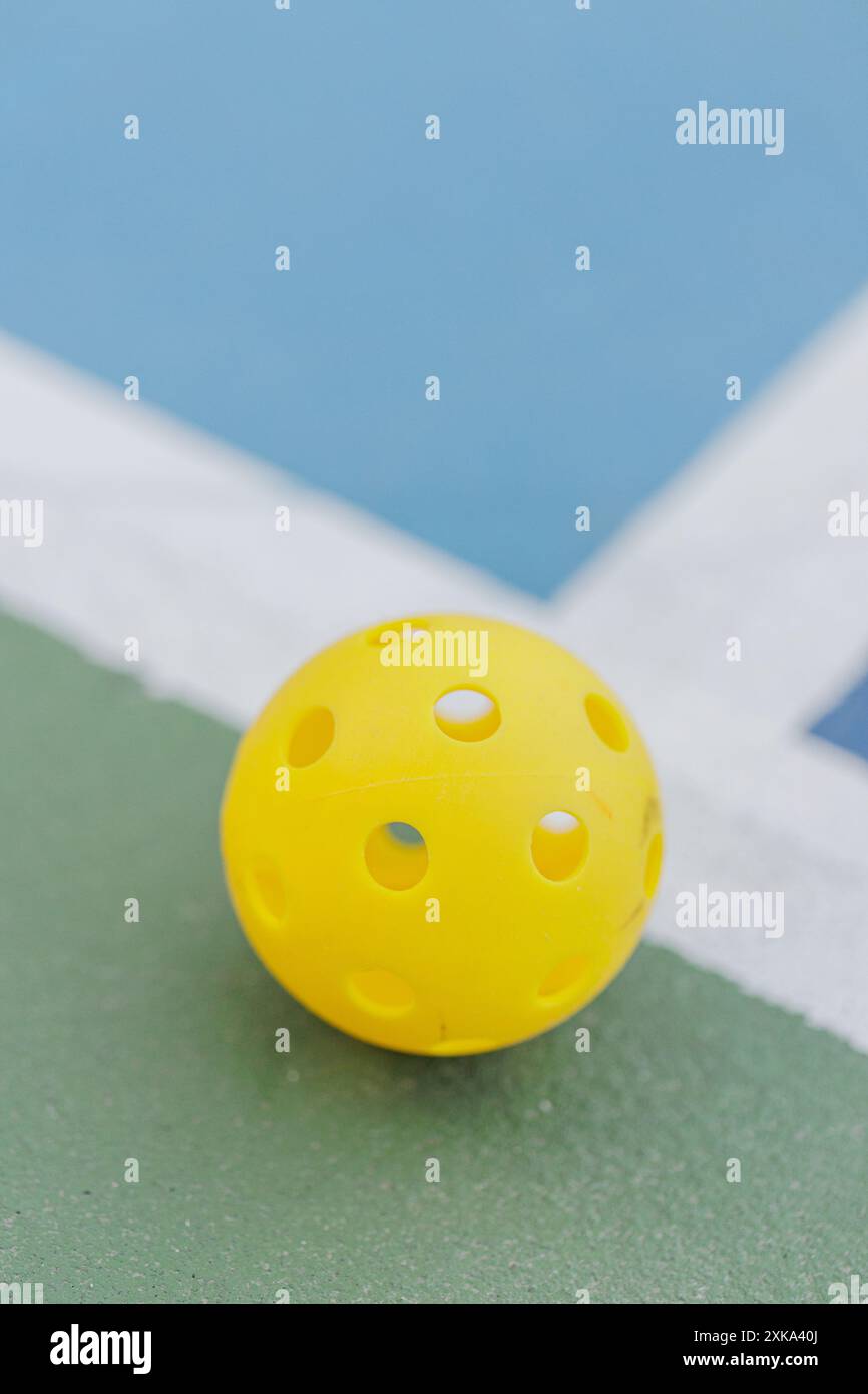 Yellow pickleball on court edge, close-up view showing its texture ...