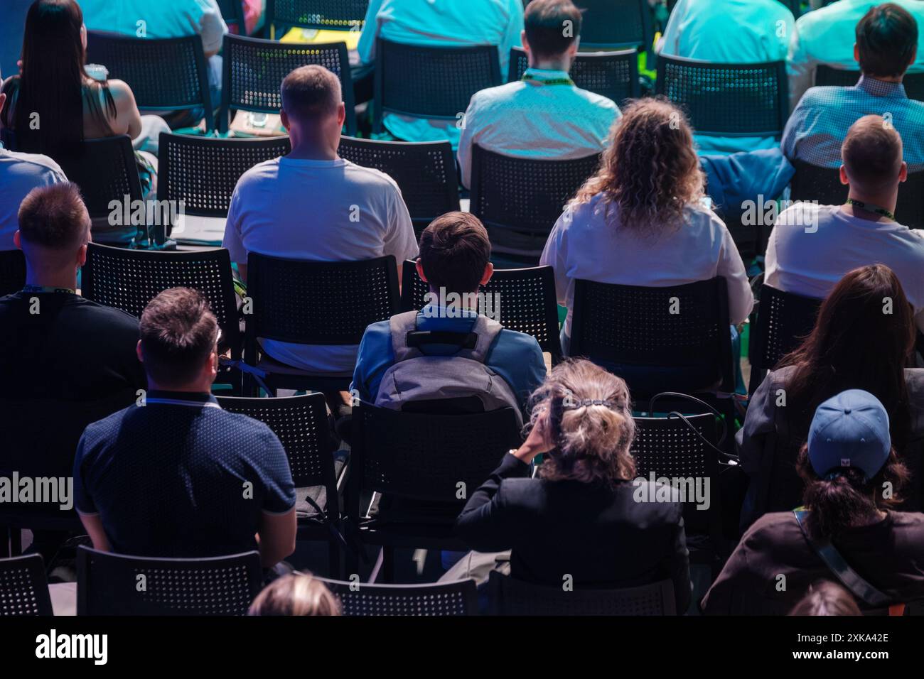 Attendees sit in rows facing forward at a conference, engrossed in the ...