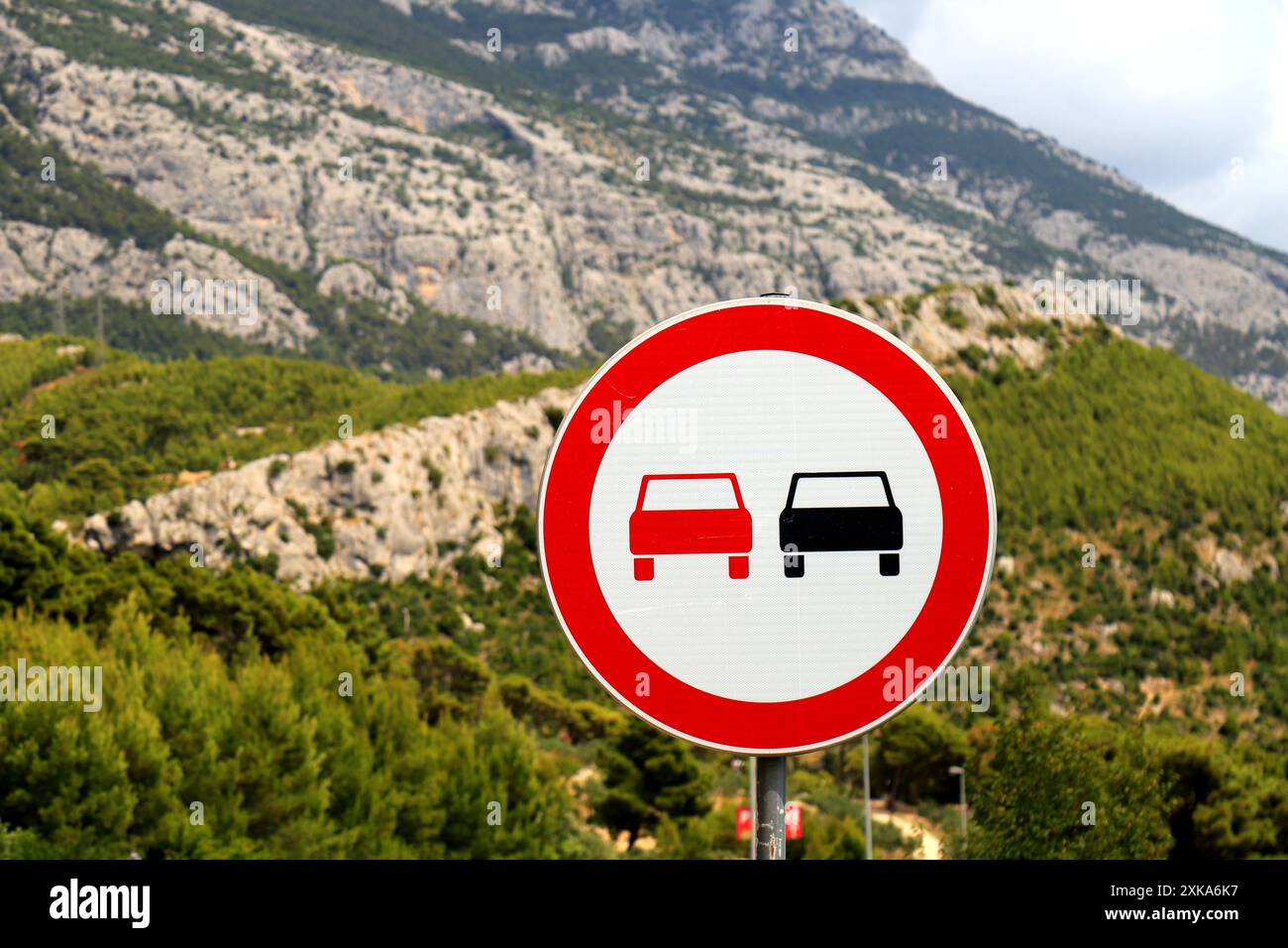 Sign - overtaking is prohibited on the side of a beautiful mountain ...