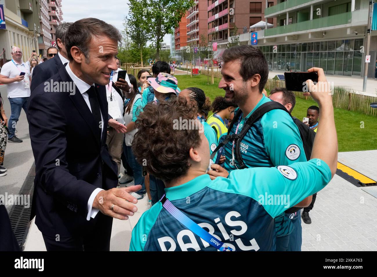 French President Emmanuel Macron poses for a selfie with volunteers as ...