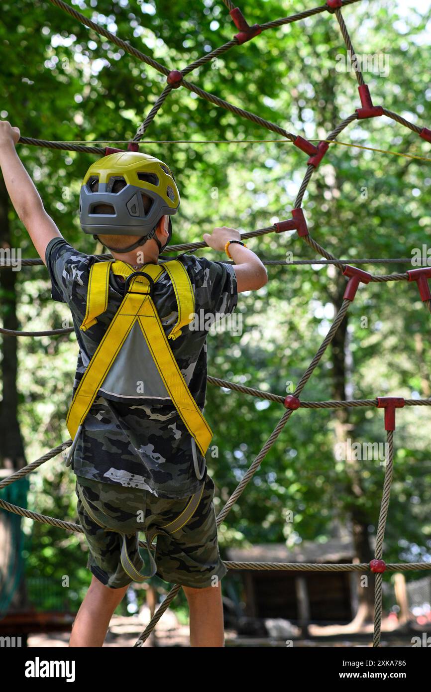 Young adventurer navigating a treetop obstacle course, demonstrating ...