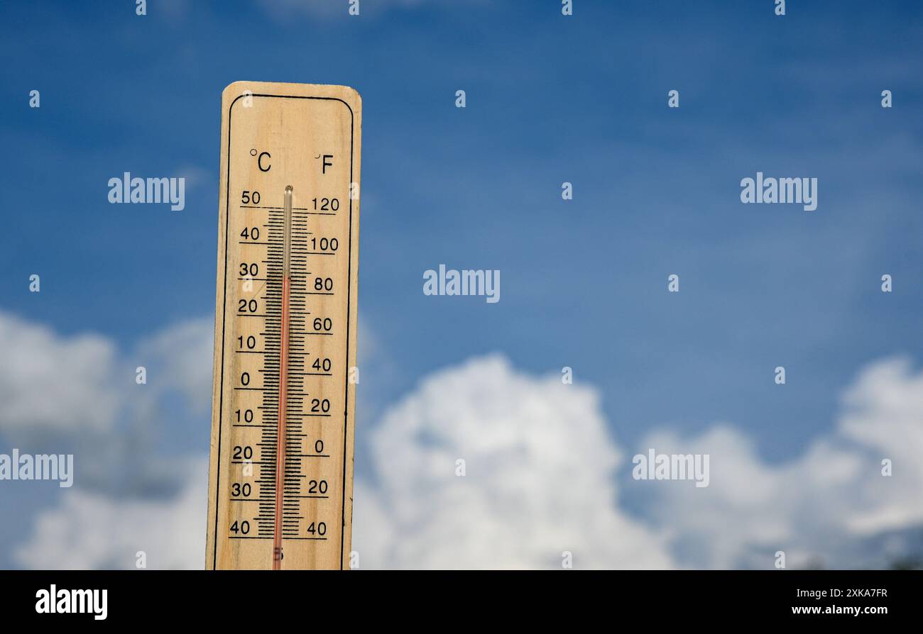 Wooden thermometer showing high temperature on a sunny day with blue ...
