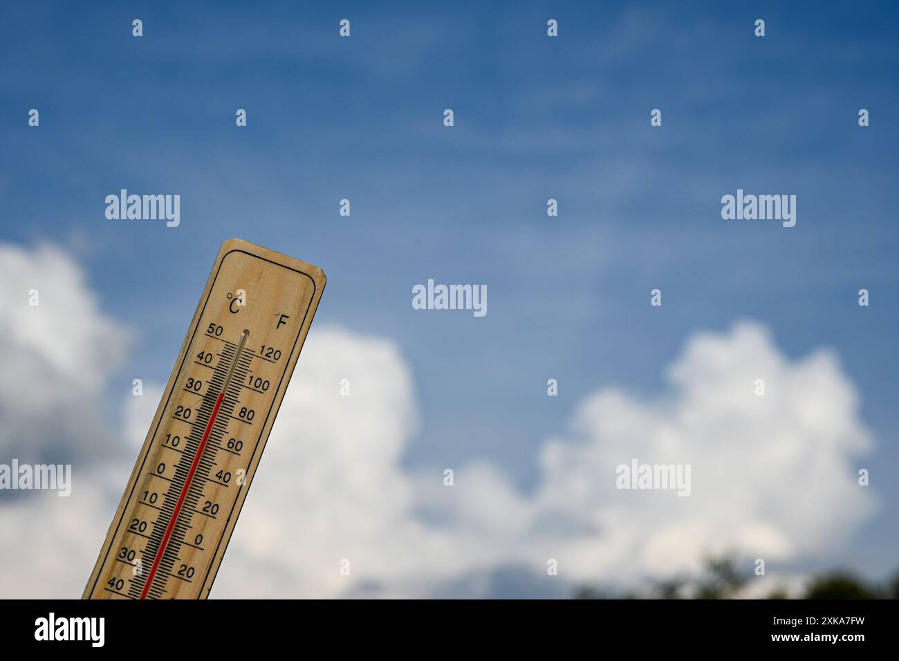 Wooden thermometer showing high temperature on a sunny day with blue ...