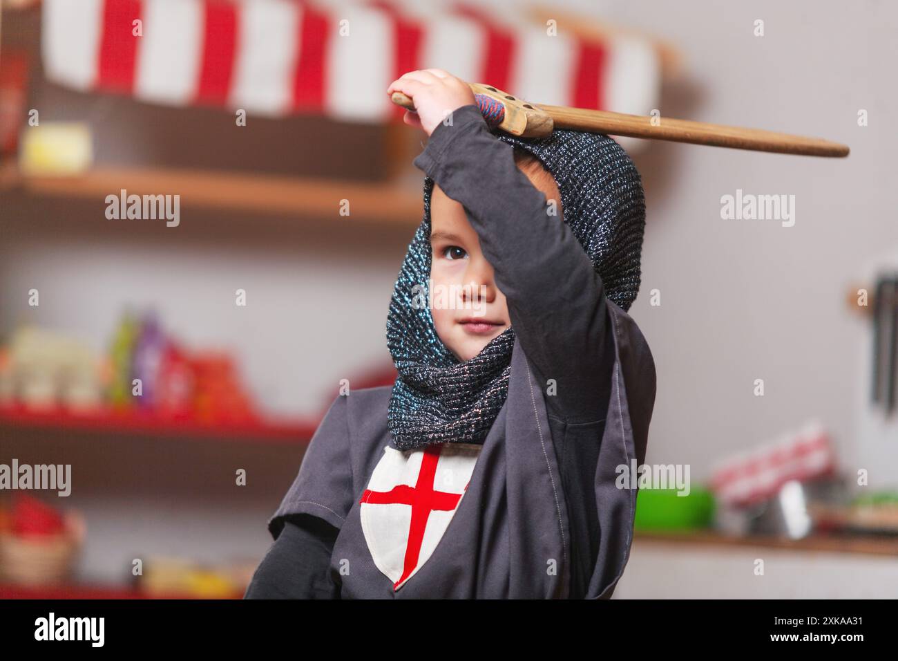 Kid playing a medieval knight in the playroom at home with a costume ...