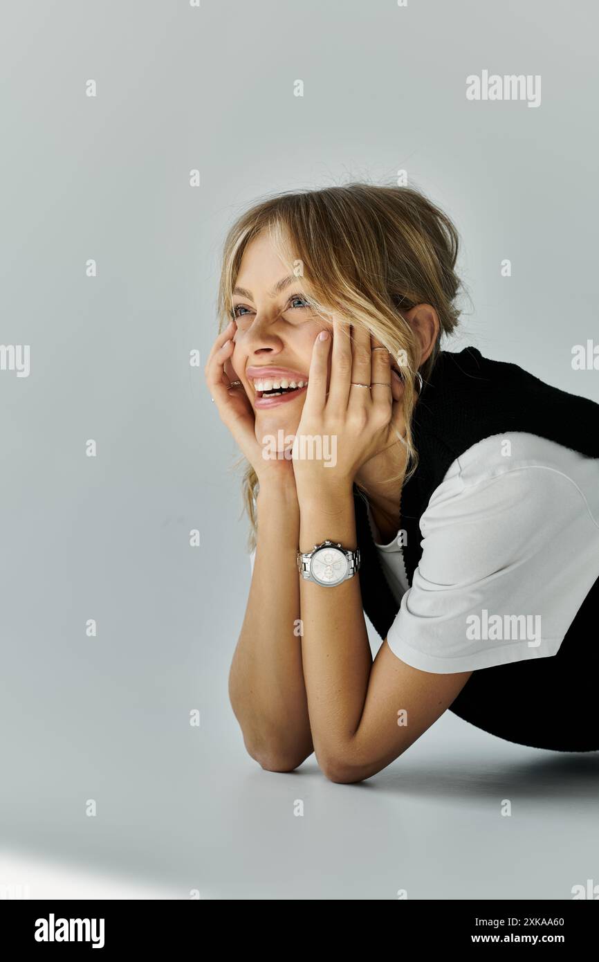 A young woman laying on the ground, hands covering her face in joy and ...