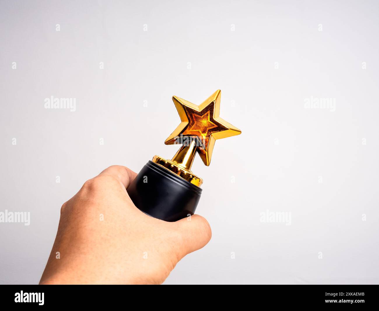 A small gold star trophy in human hand isolated on white background ...