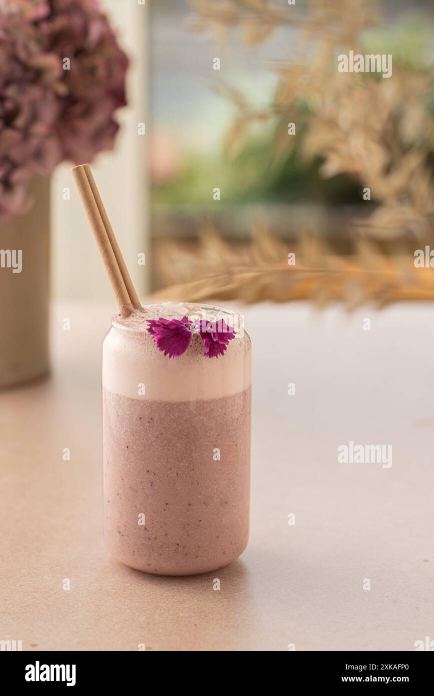 Strawberry vegan smoothie decorated with coconut and edible flower on a ...