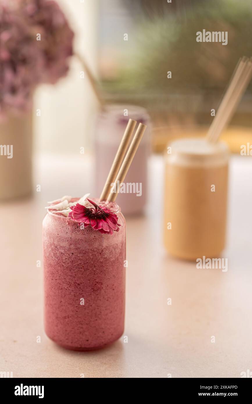 Red fruits vegan smoothie decorated with coconut and edible flower on a ...