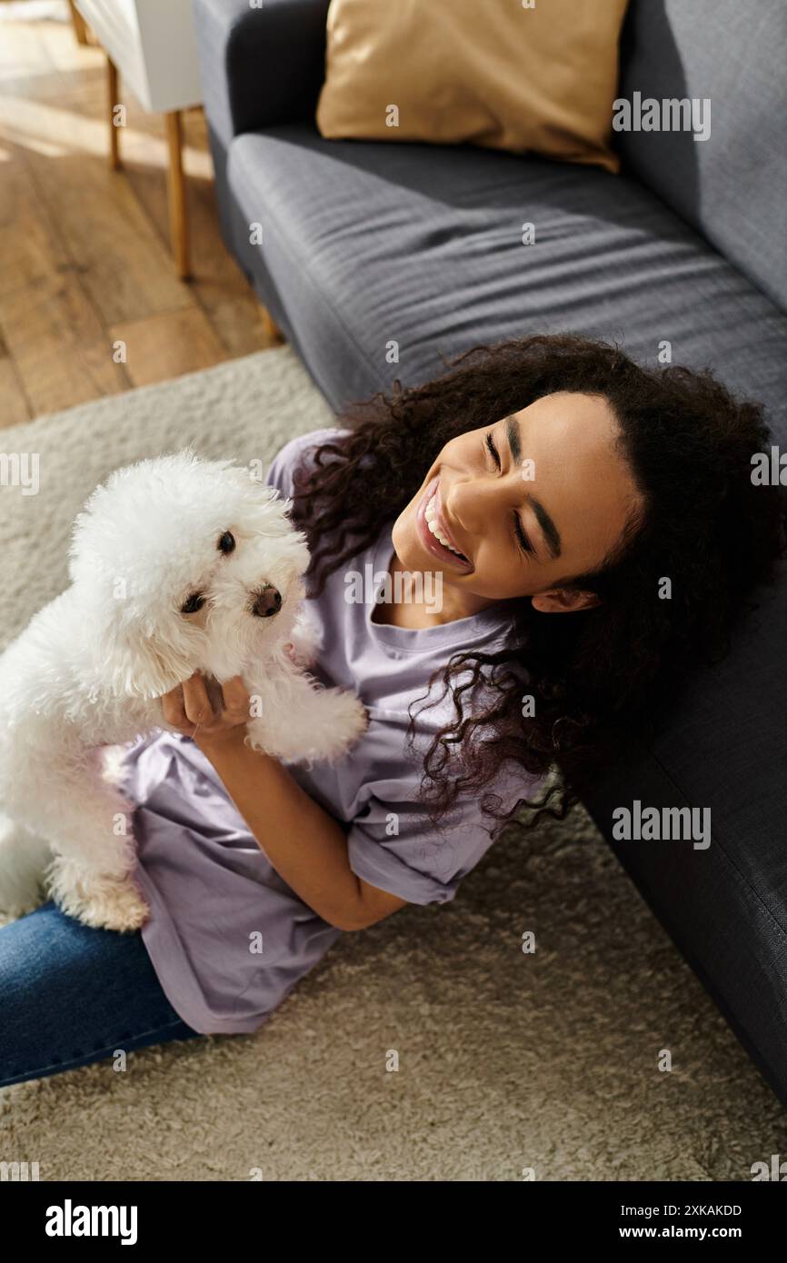 Woman sitting on floor, cradling white Bichon Frise dog Stock Photo - Alamy