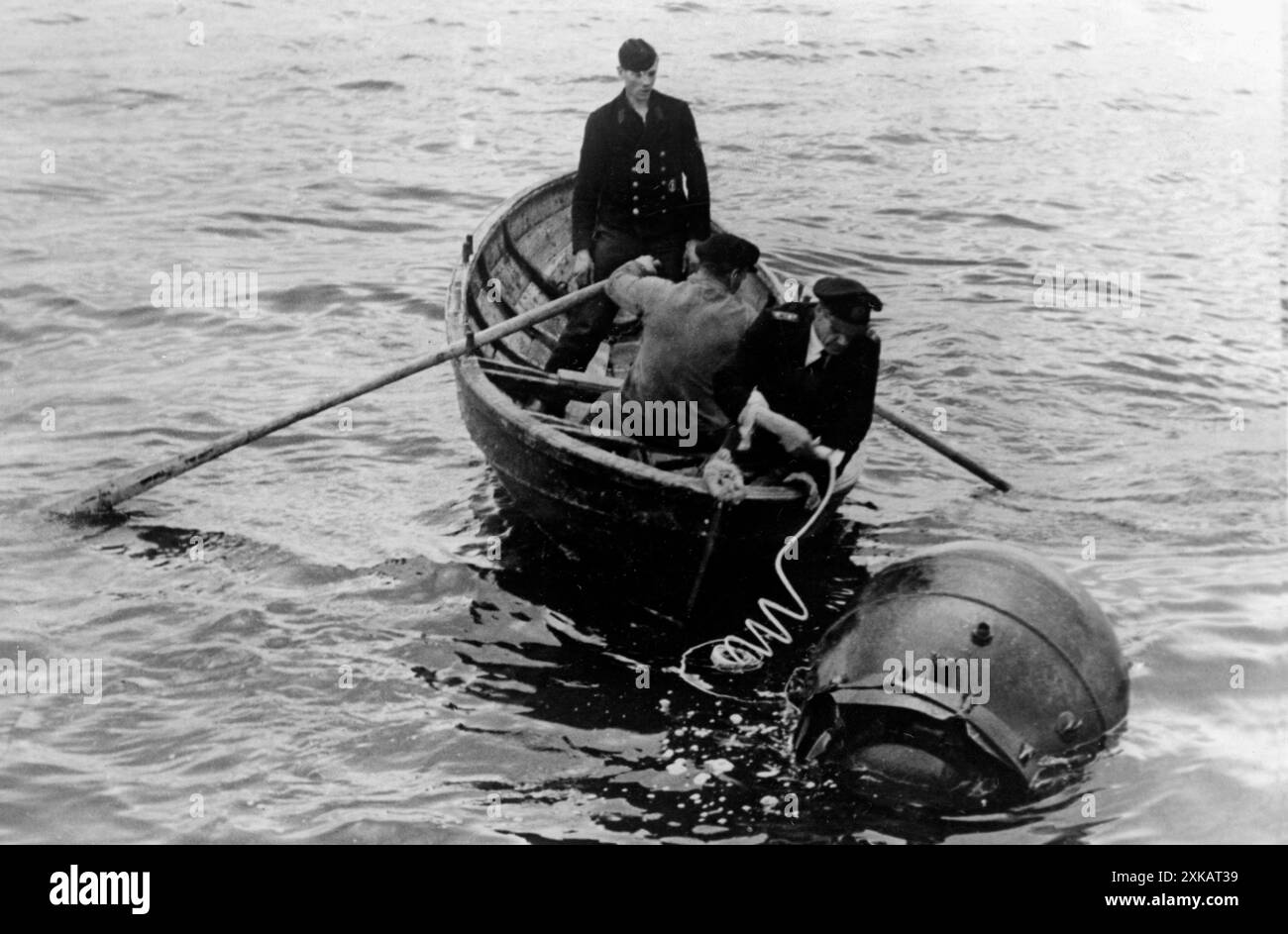 German soldiers attach an explosive charge and fuse to a sea mine that ...