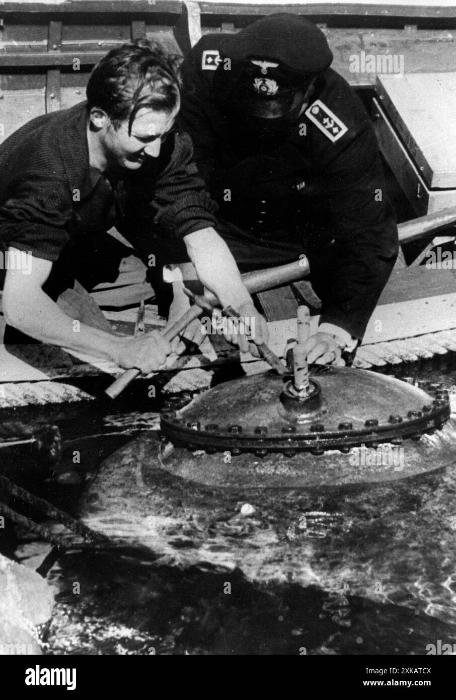 German soldiers defusing a sea mine torn loose from its anchor rope ...